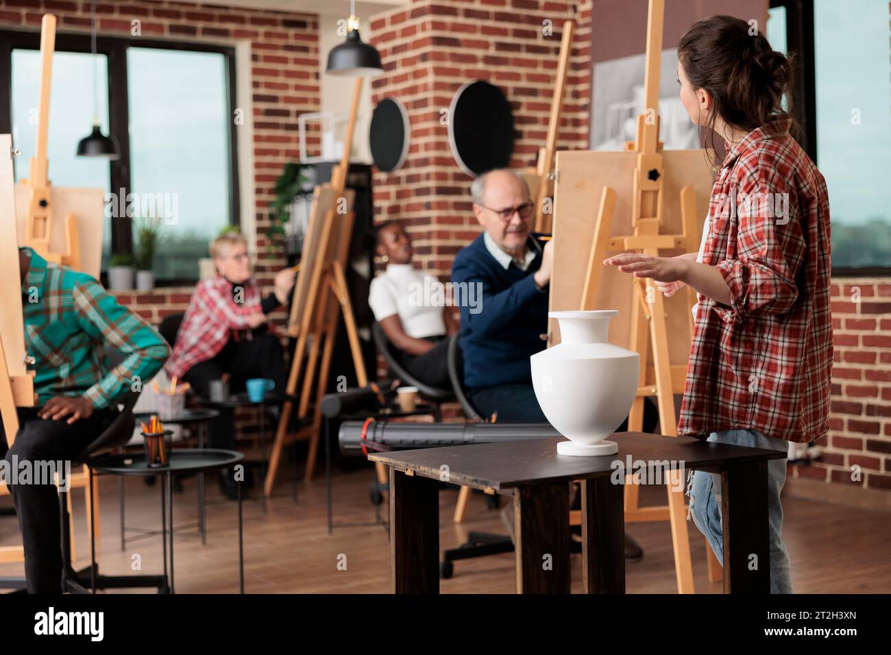 Group drawing classes. Young woman artist teaching art to people from ...
