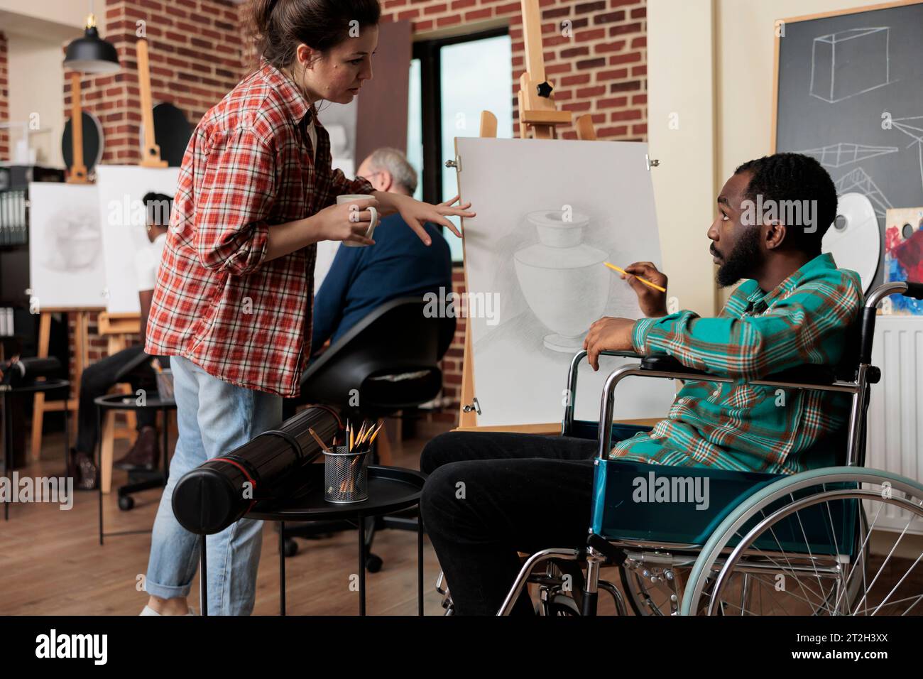 African American disabled guy talking with teacher during group drawing ...