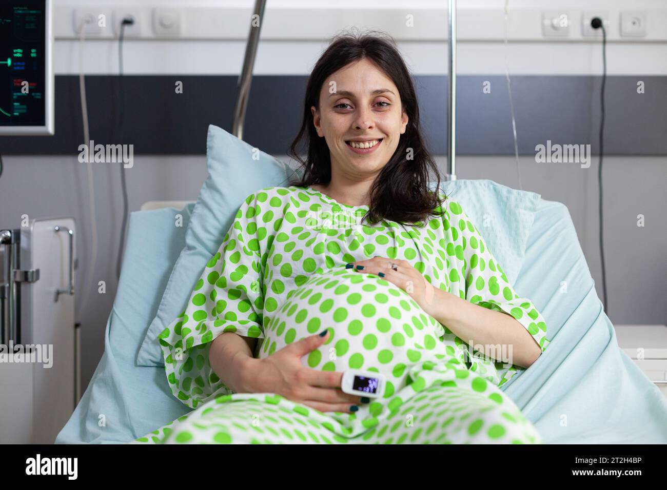 Portrait of smiling patient with pregnancy, waiting to receive medical ...