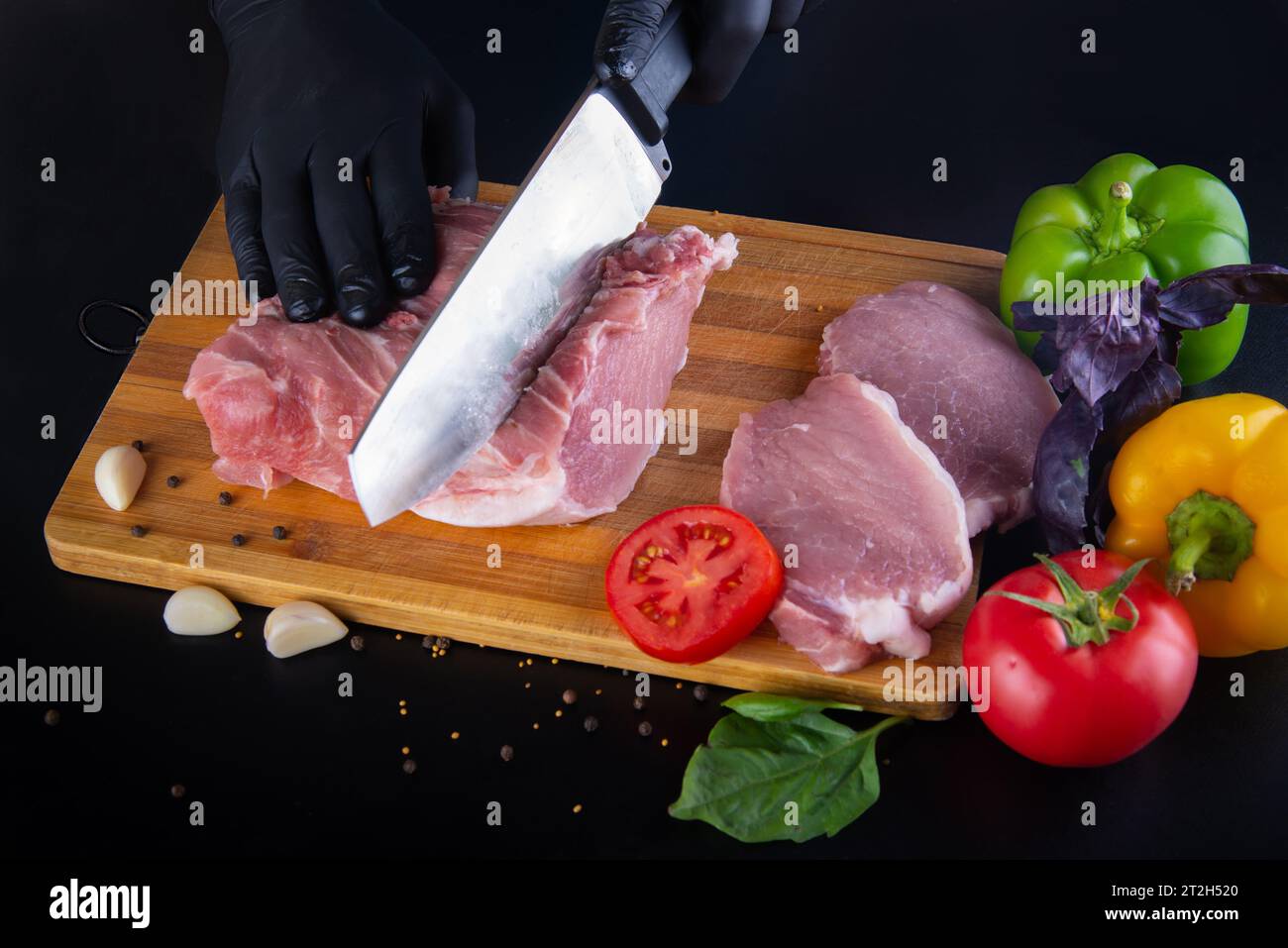 Cooking process. Chief cutting meat with knif on black background. Red ...