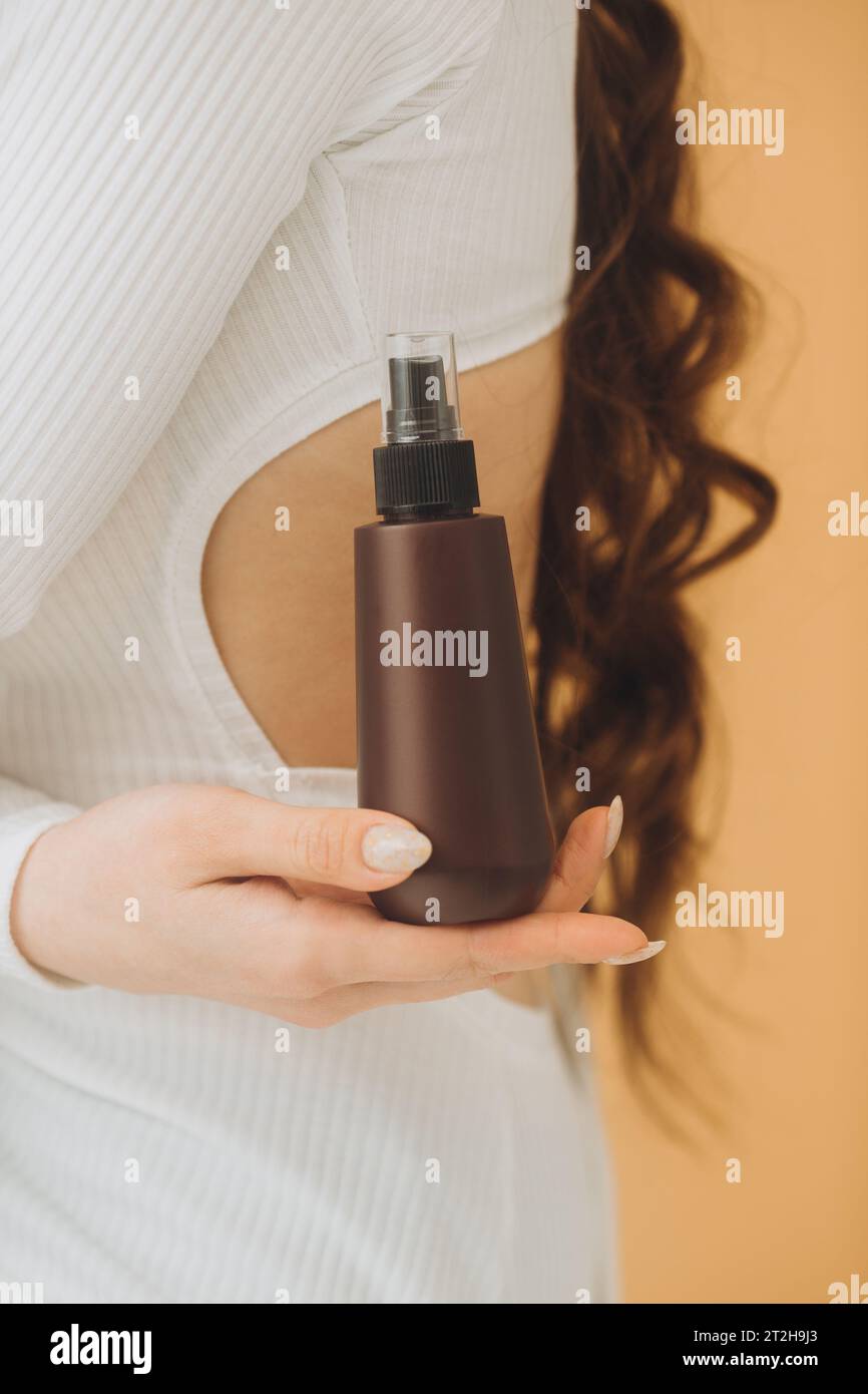 Young model holding cosmetic lotion isolated on beige Stock Photo - Alamy