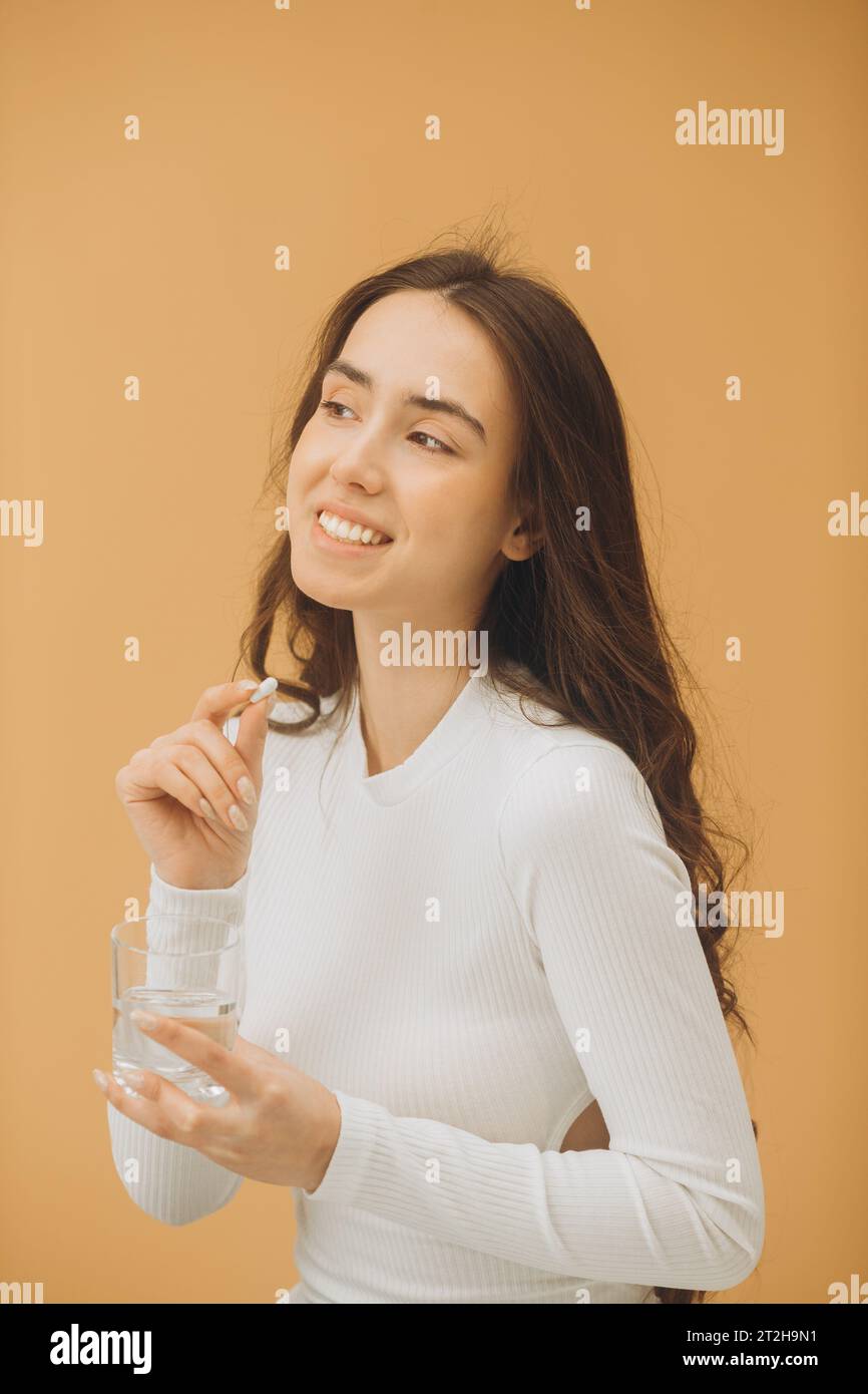 Pretty young woman taking vitamins. A woman is holding a pill and a ...
