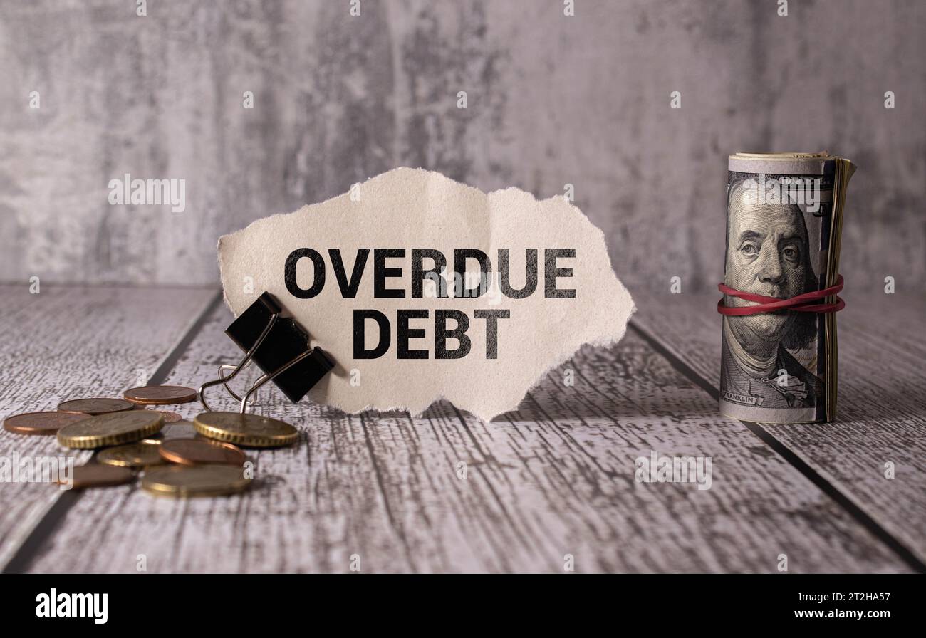money and torn paper that says OVERDUE DEBT Stock Photo - Alamy