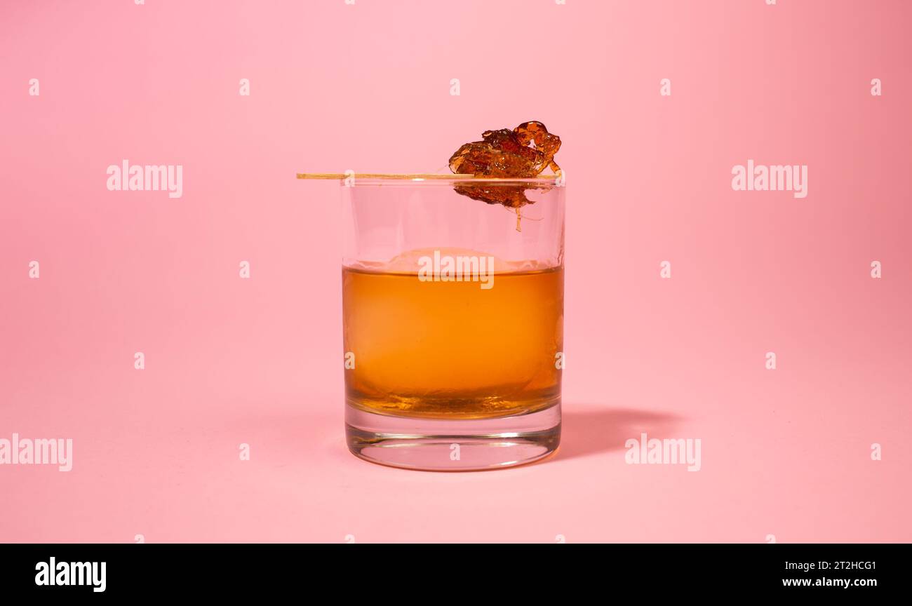 A clear glass of a refreshing cocktail with a lollipop garnish against ...