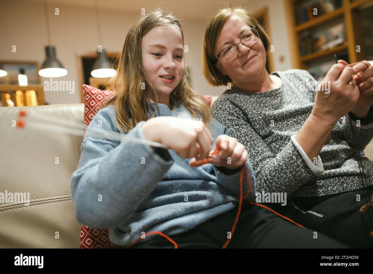 Grandmother and teenage granddaughter knitting on a sofa. Grandma ...