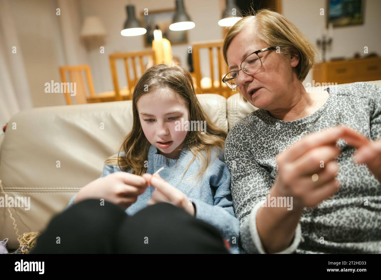 Grandmother and teenage granddaughter knitting on a sofa. Grandma ...