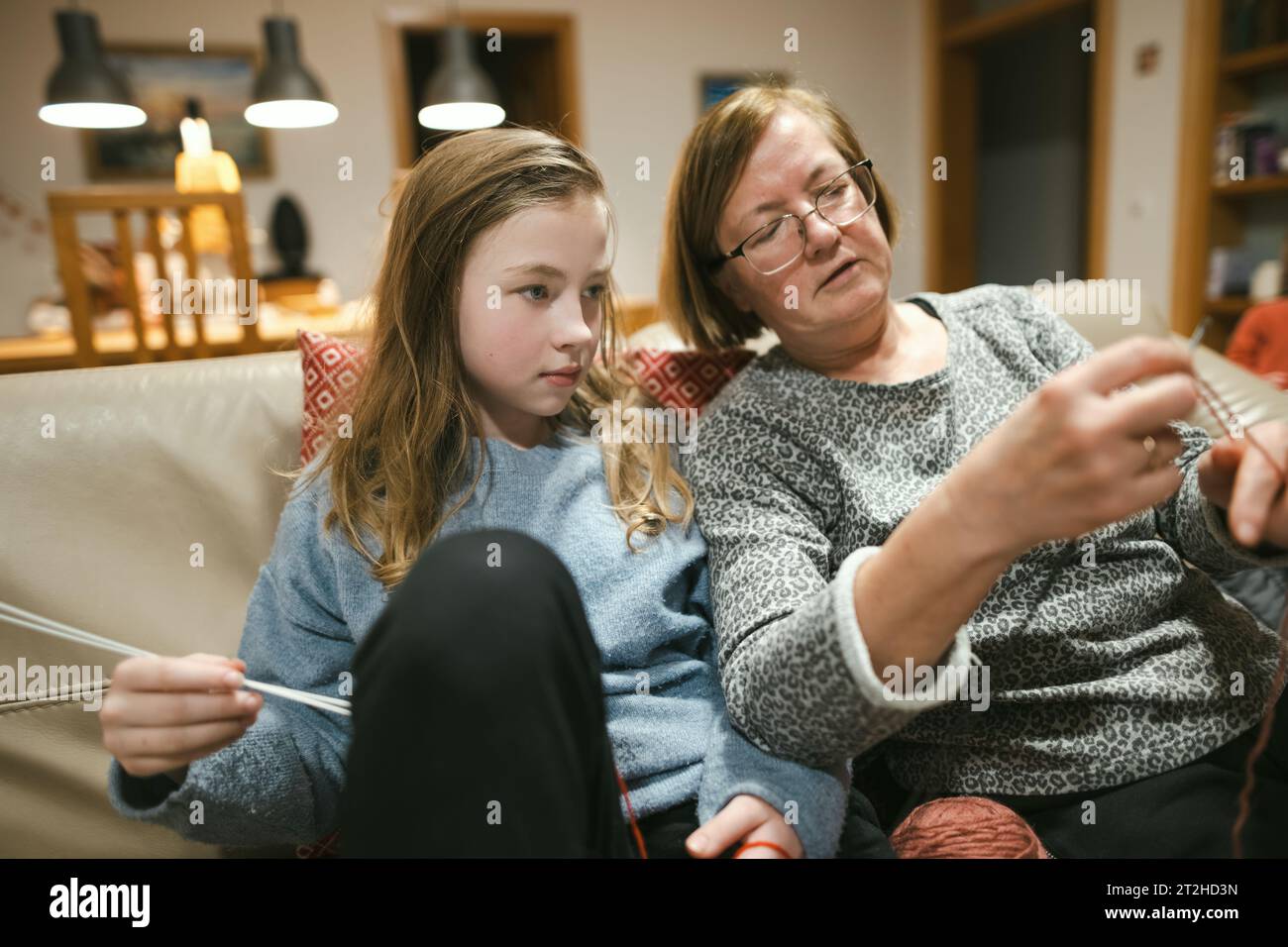 Grandmother and teenage granddaughter knitting on a sofa. Grandma ...