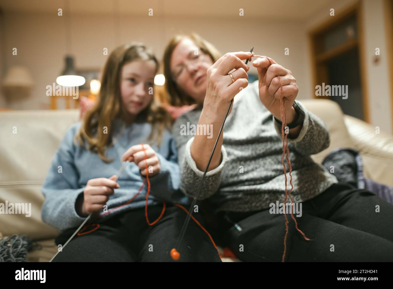 Grandmother and teenage granddaughter knitting on a sofa. Grandma ...