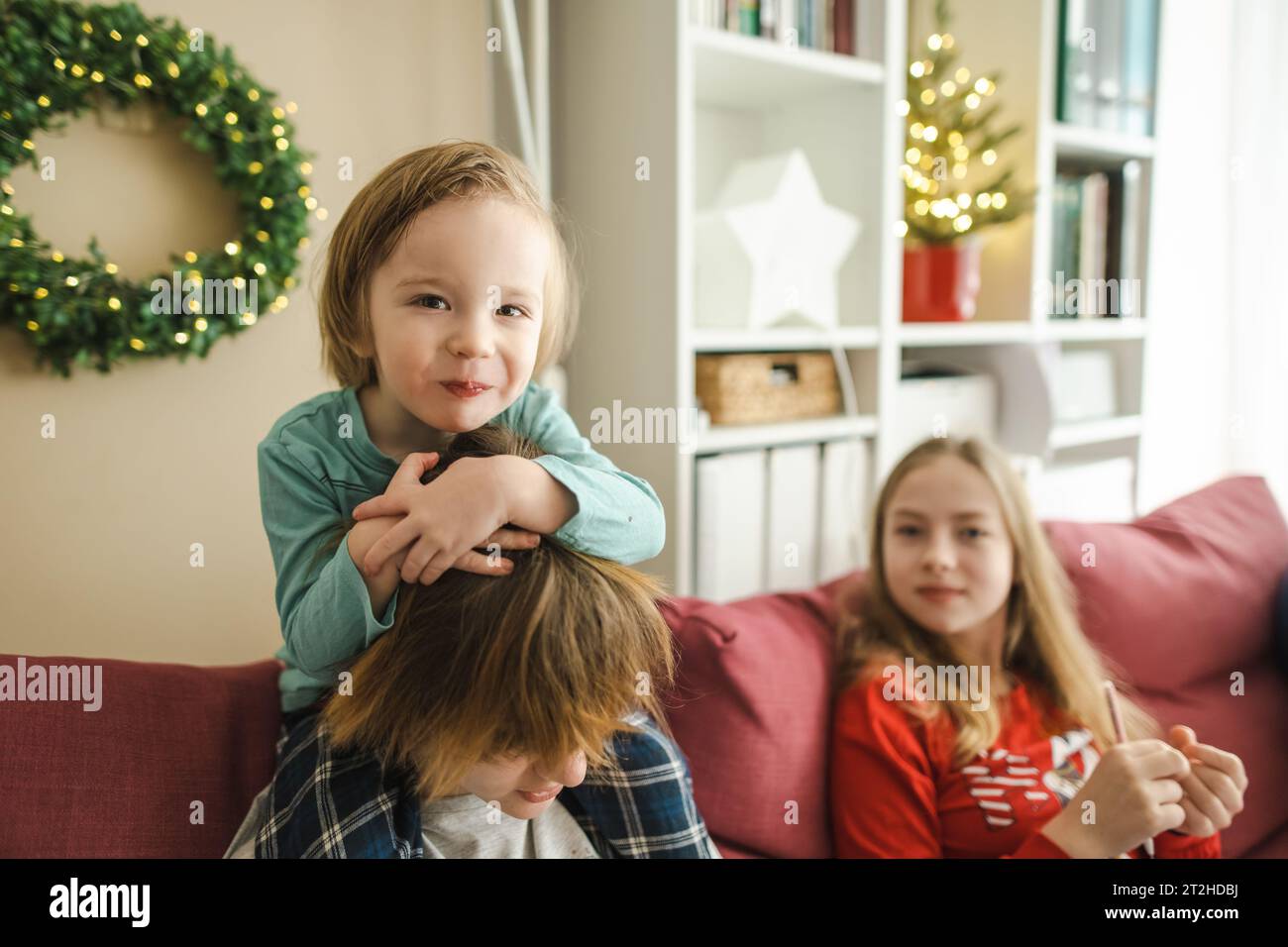 Two teenage sisters and their toddler brother snuggling up on the sofa ...