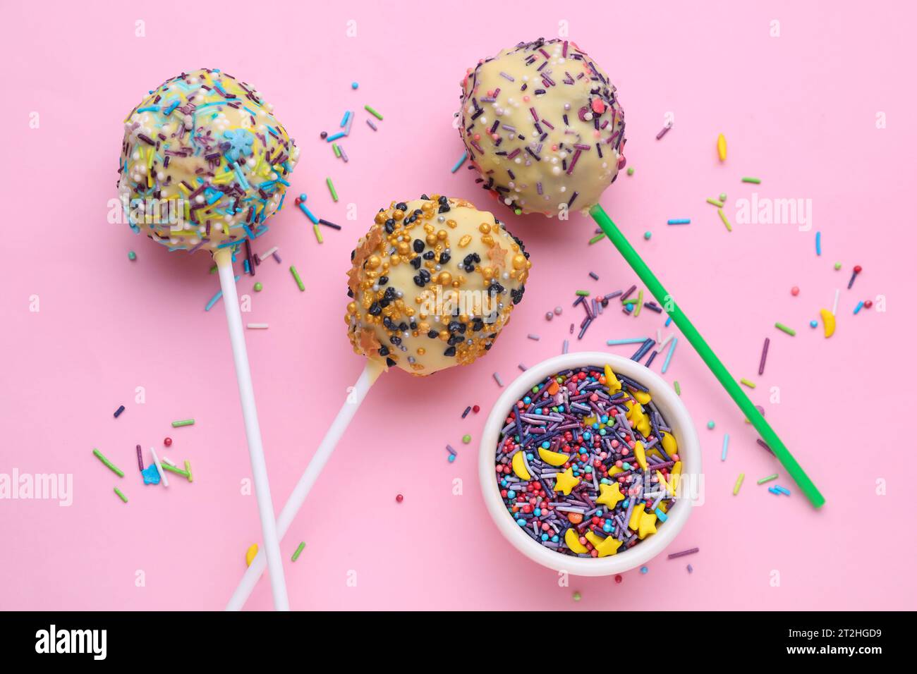 Delicious confectionery. Sweet cake pops and sprinkles on pale pink ...