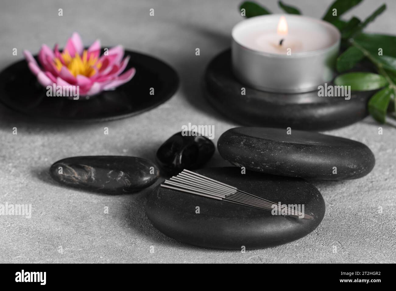 Stones with acupuncture needles on grey textured table Stock Photo - Alamy