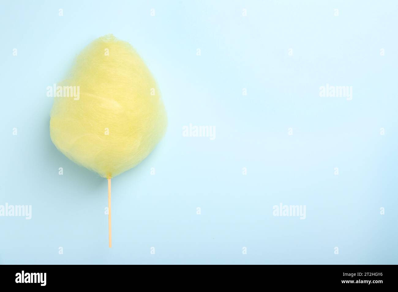 One sweet yellow cotton candy on light blue background, top view. Space ...