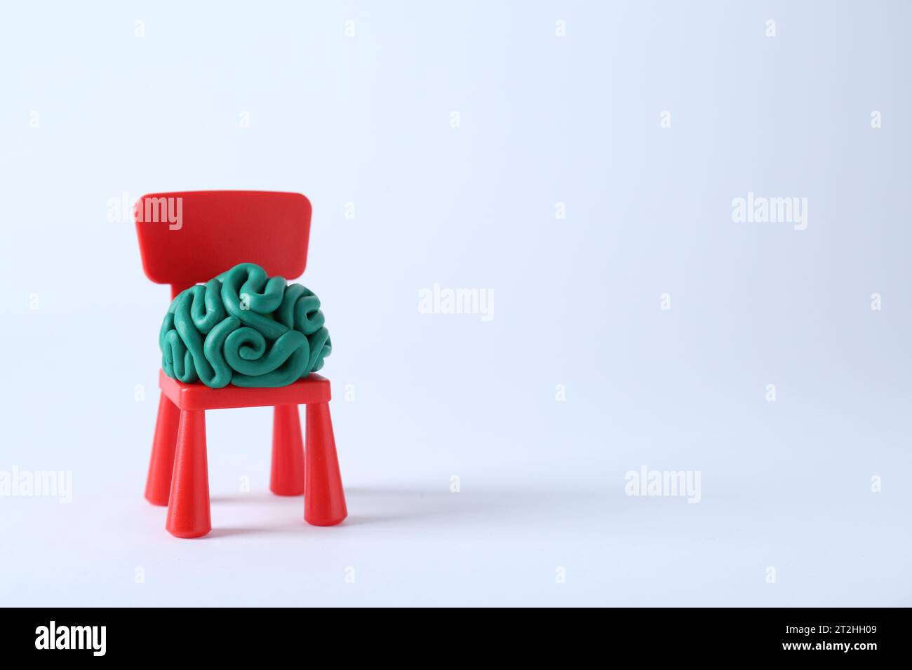 Brain made of plasticine on mini chair against white background. Space ...