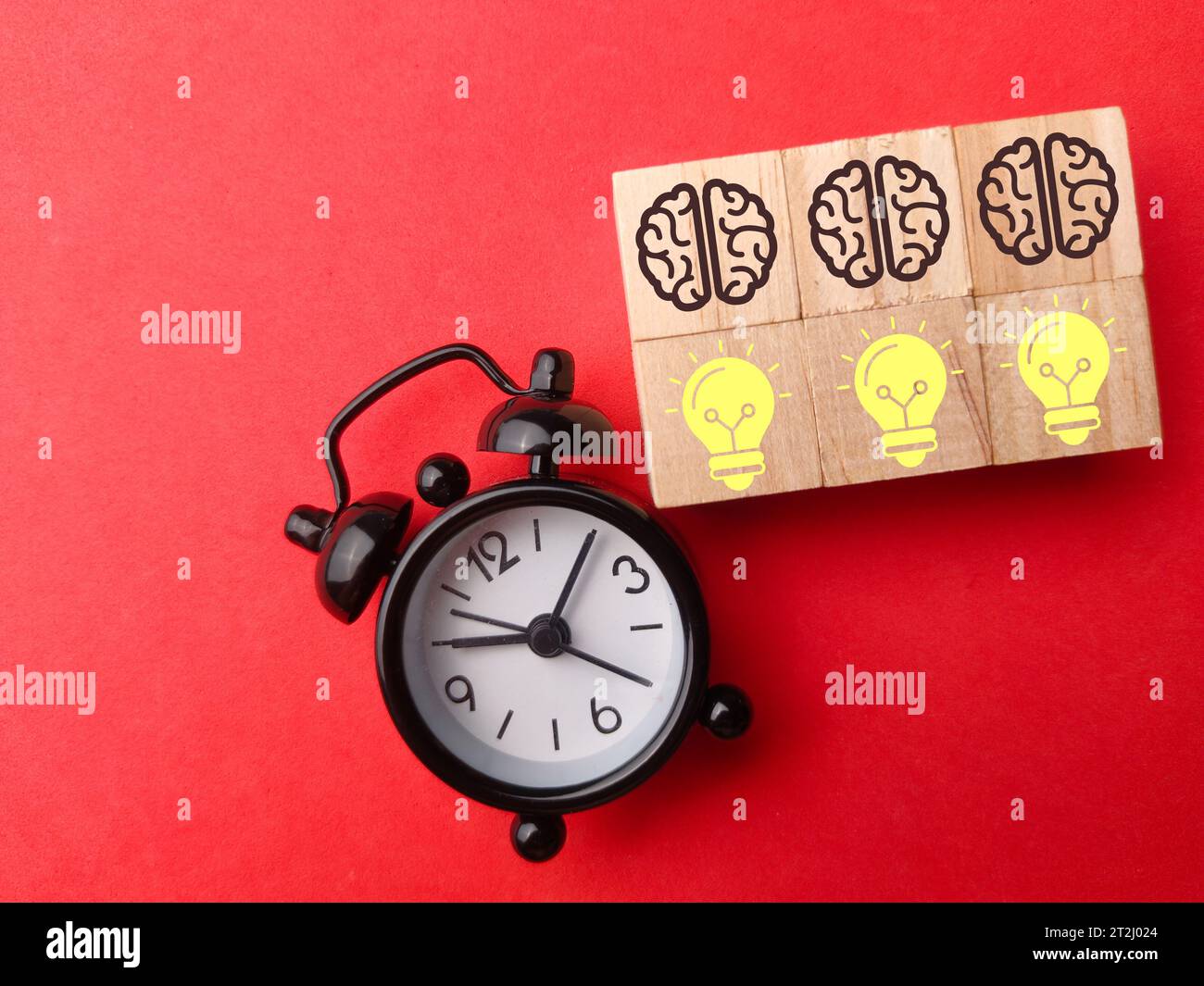 Alarm clock and wooden block with bulb and brain icons. a combination ...
