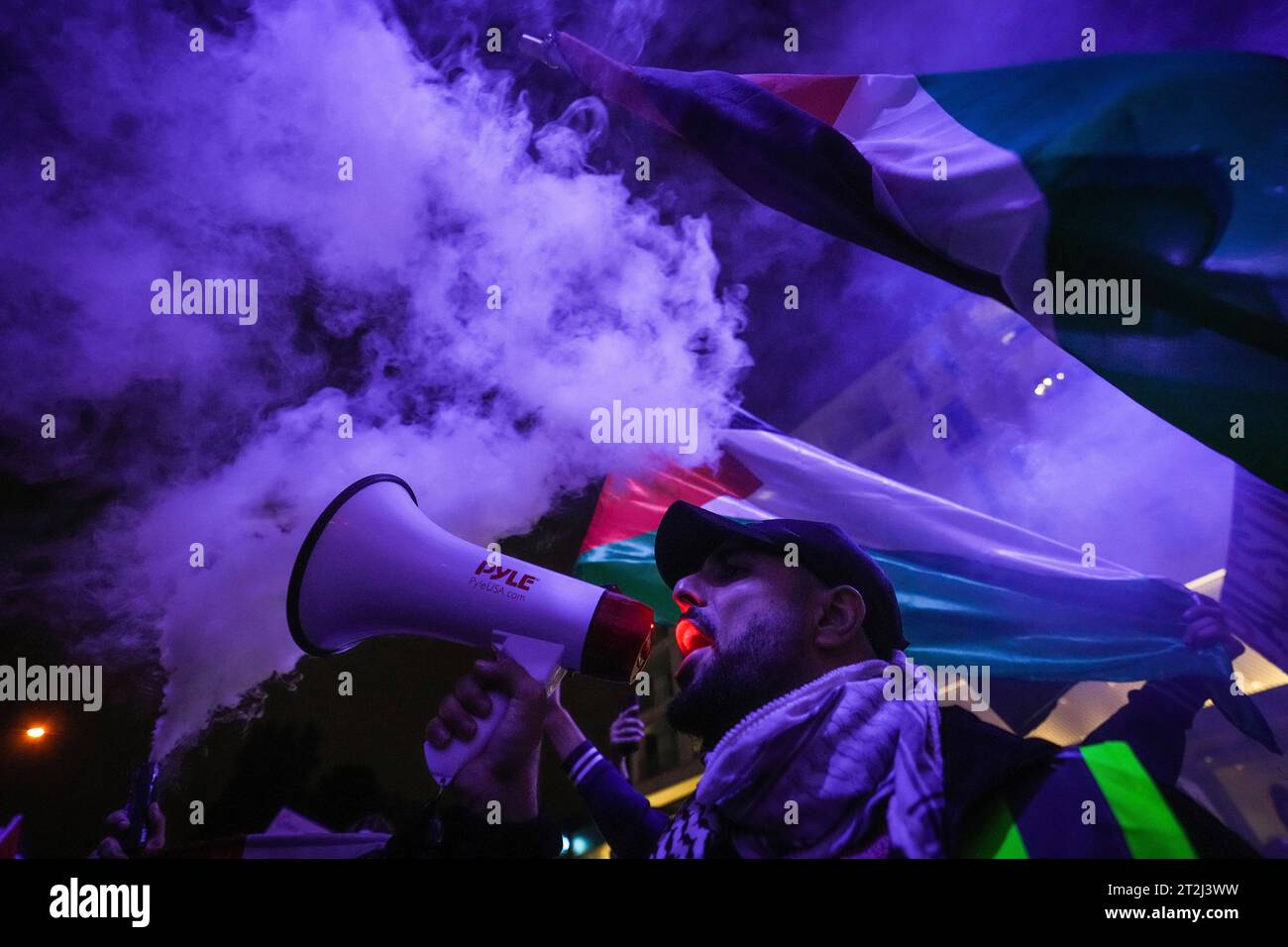 A man uses a bullhorn as smoke bombs are set off during a demonstration ...