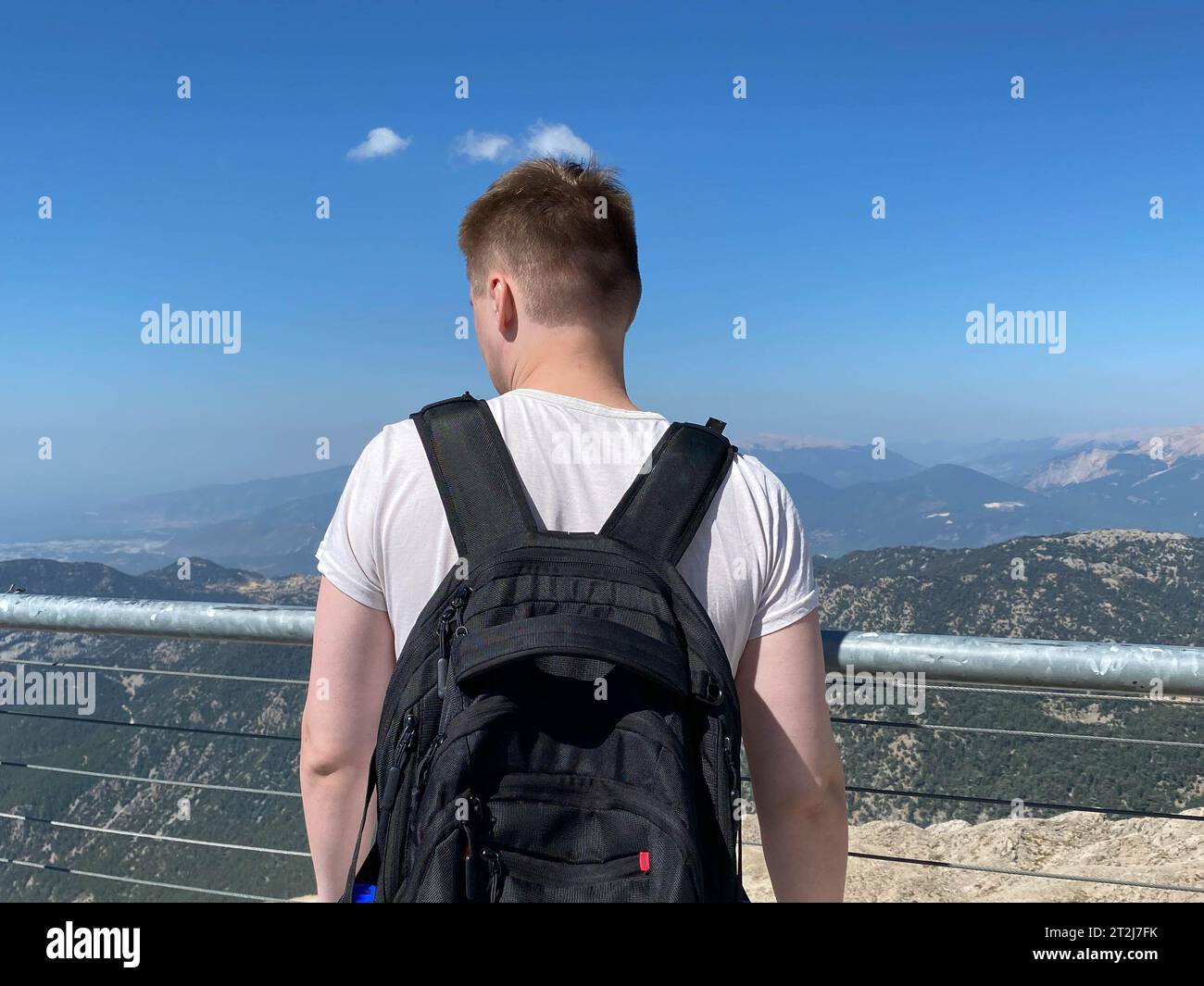 man with backpack standing on observation deck in mountains blurred ...