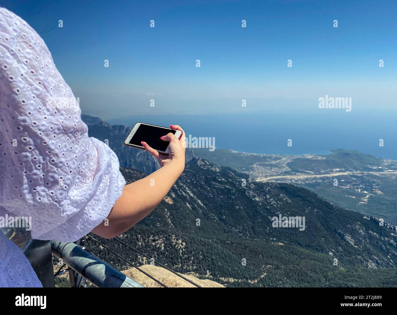 a girl in a white dress with long, dark hair on the observation deck takes a photo of the ...