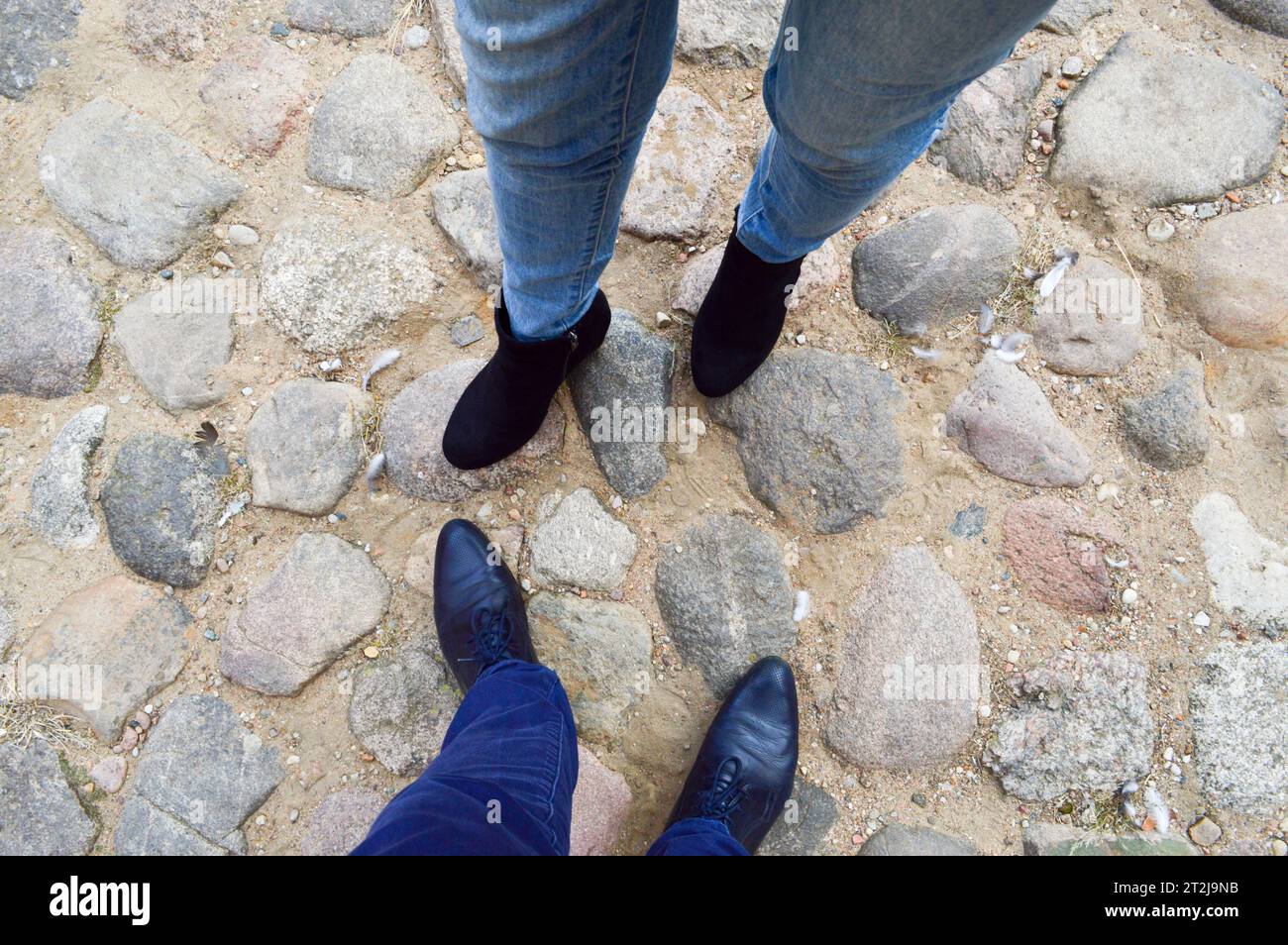 Male and female legs in leather shoes, boots on a stone road of large ...