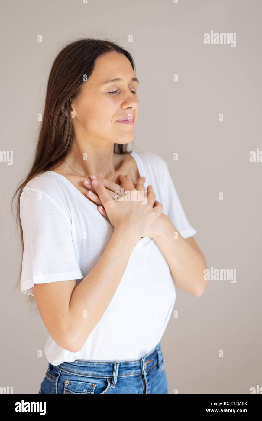 Woman with hands on chest doing breathing exercise at home Stock Photo ...