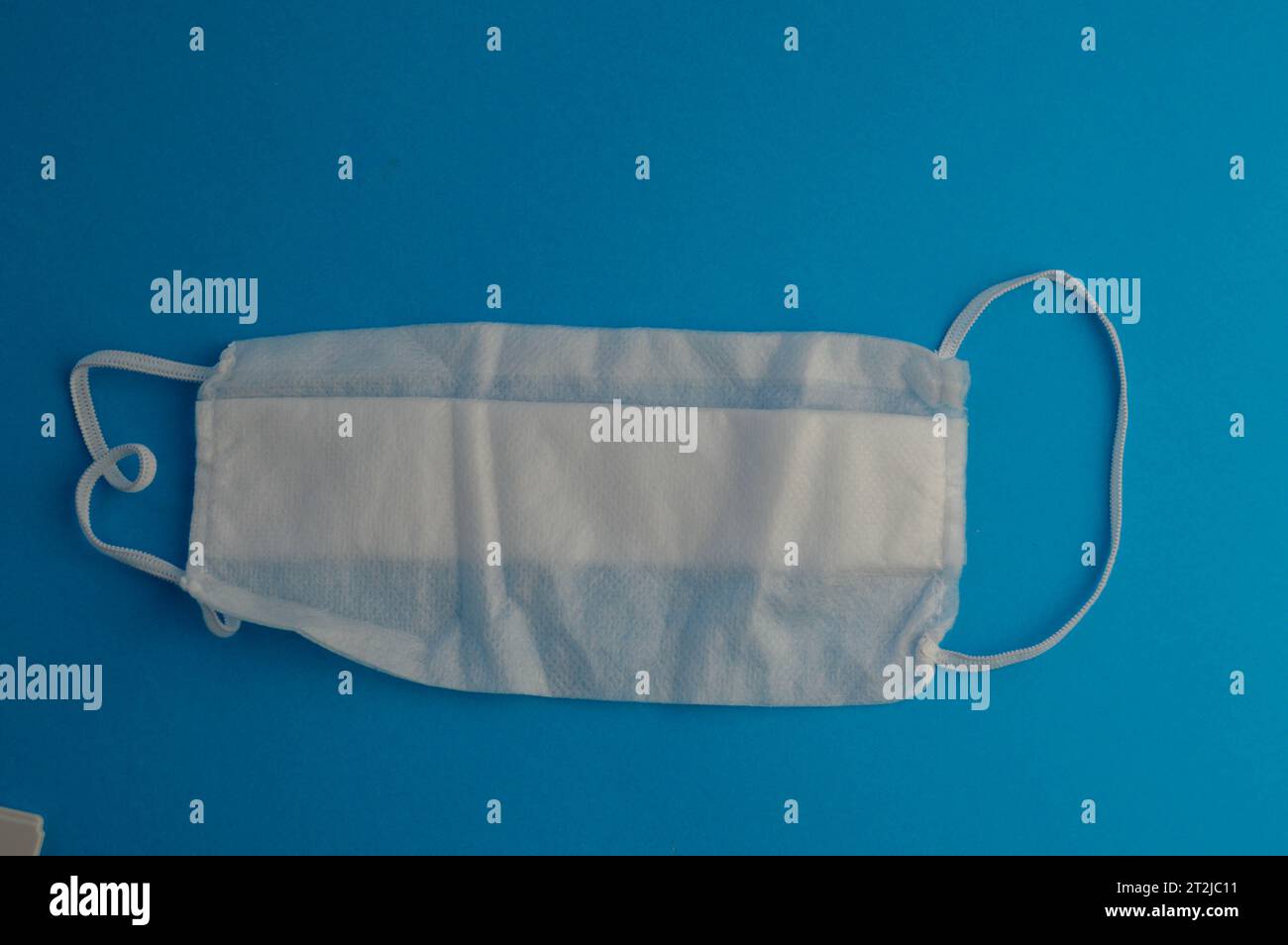 white disposable mask on a blue matte background. mask made of thin ...