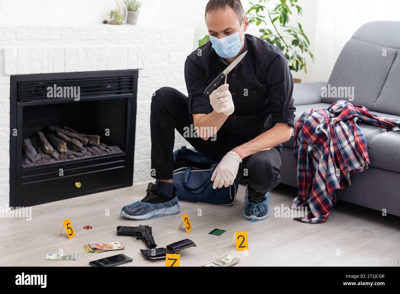 Young policeman collecting evidence standing behhind yellow crime scene ...