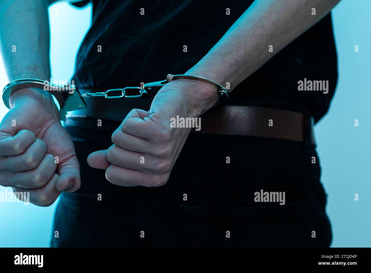 Male hands in handcuffs black background Stock Photo - Alamy