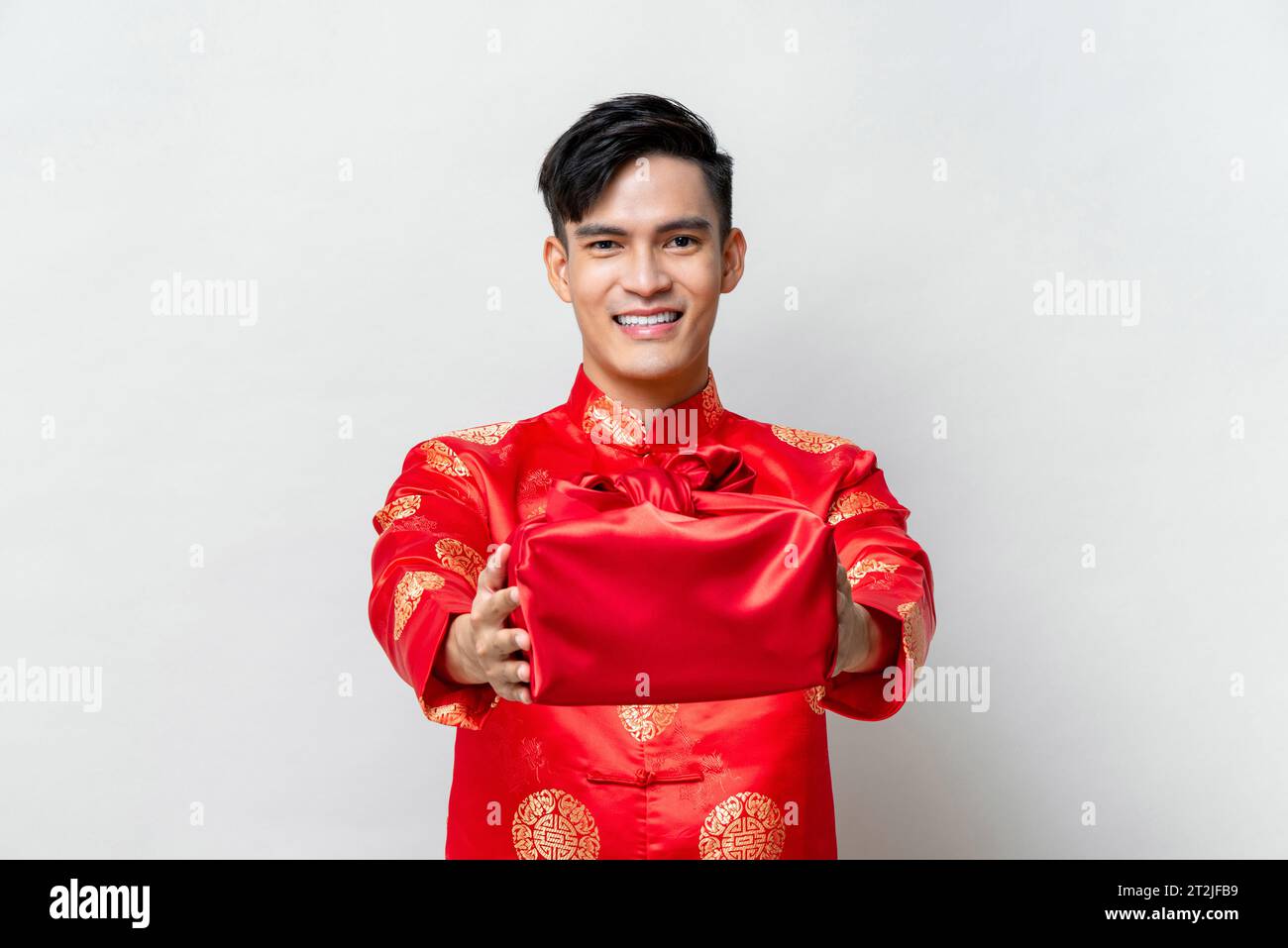 Handsome smiling Asian man giving Chinese new year gift in isolated ...