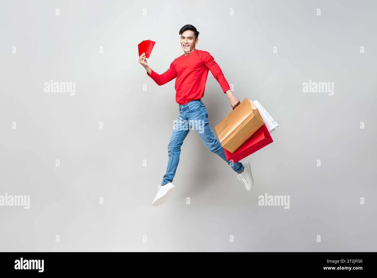 Surprised Asian man holding bags and red envelope Ang Pow jumping in ...