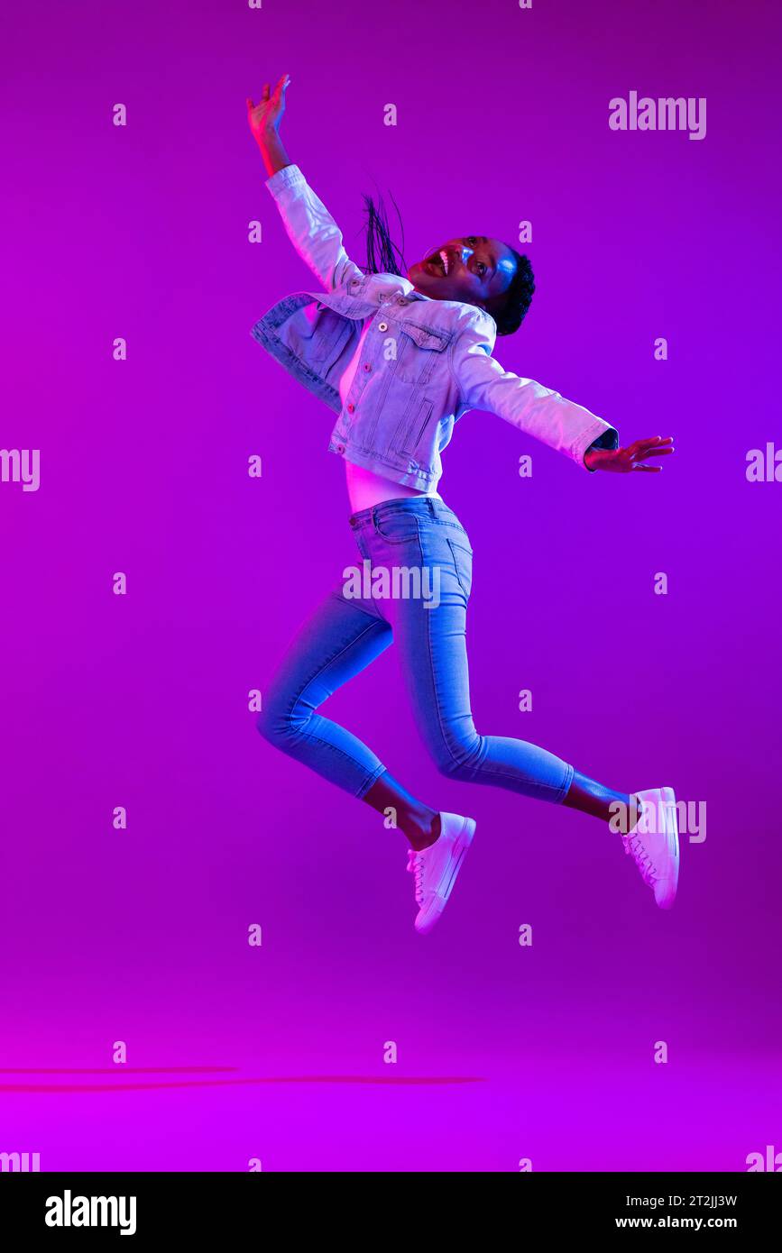 Full body portrait of ecstatic African-American woman jumping in modern ...