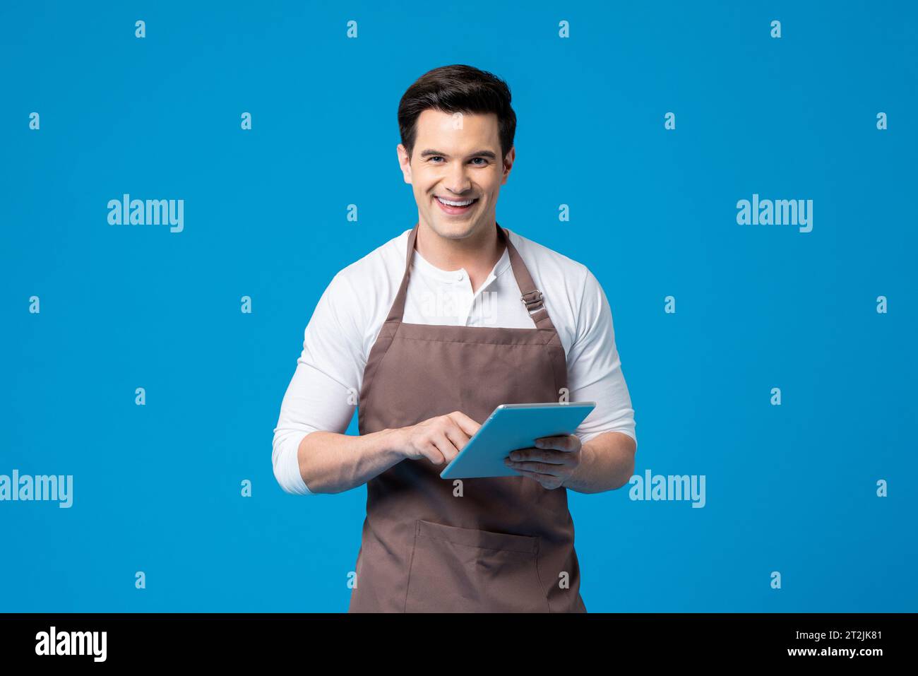 Serviced minded Caucasian male waiter with apron holding tablet in his ...