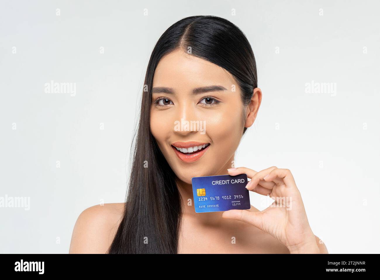 Beauty shot of cheerful Asian female with long dark hair showing credit card on white isolated ...