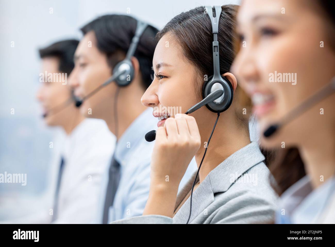 Side view of positive Asian woman telemarketer wearing headset with ...