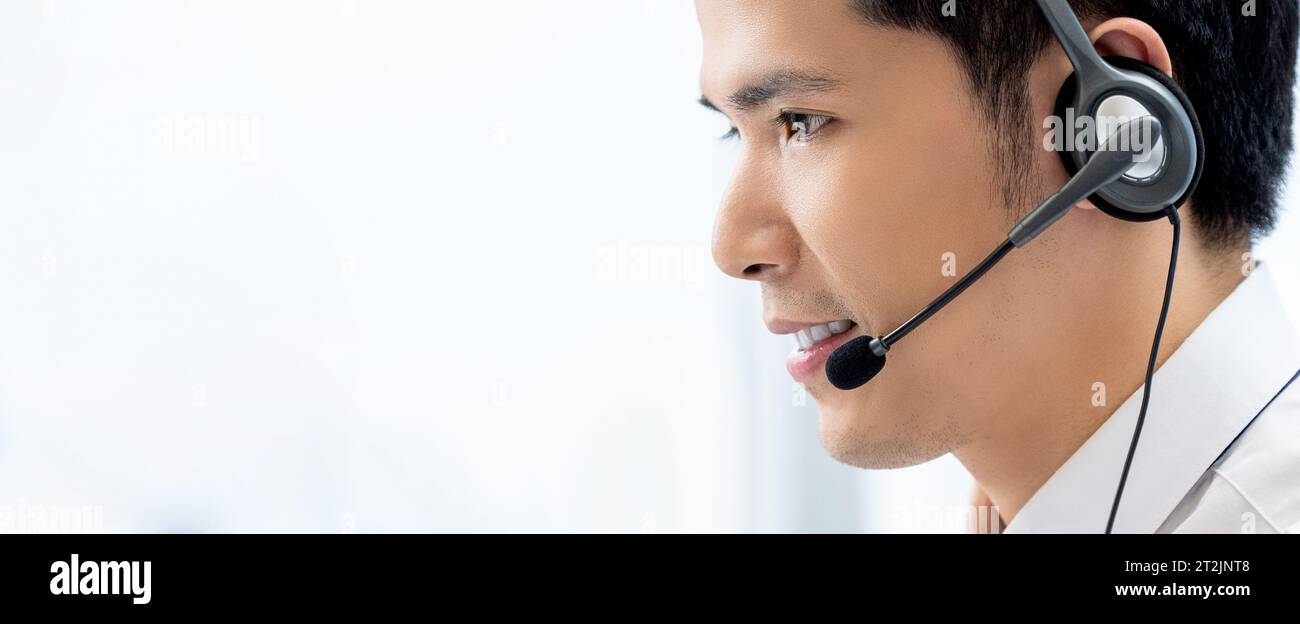 Side view of Asian man worker in headset with microphone speaking with ...