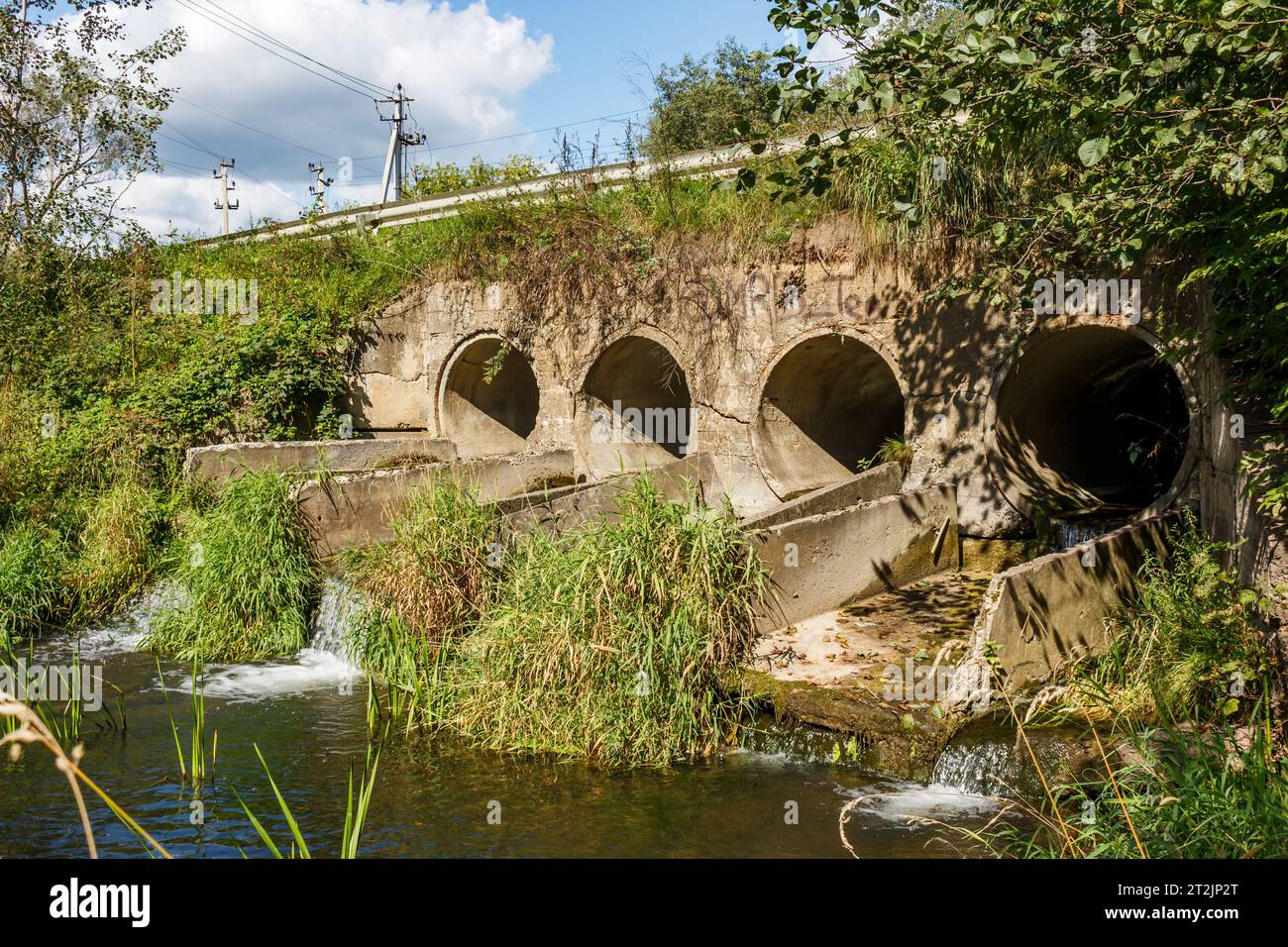 Culvert system of four pipes on the river under the road Stock Photo ...