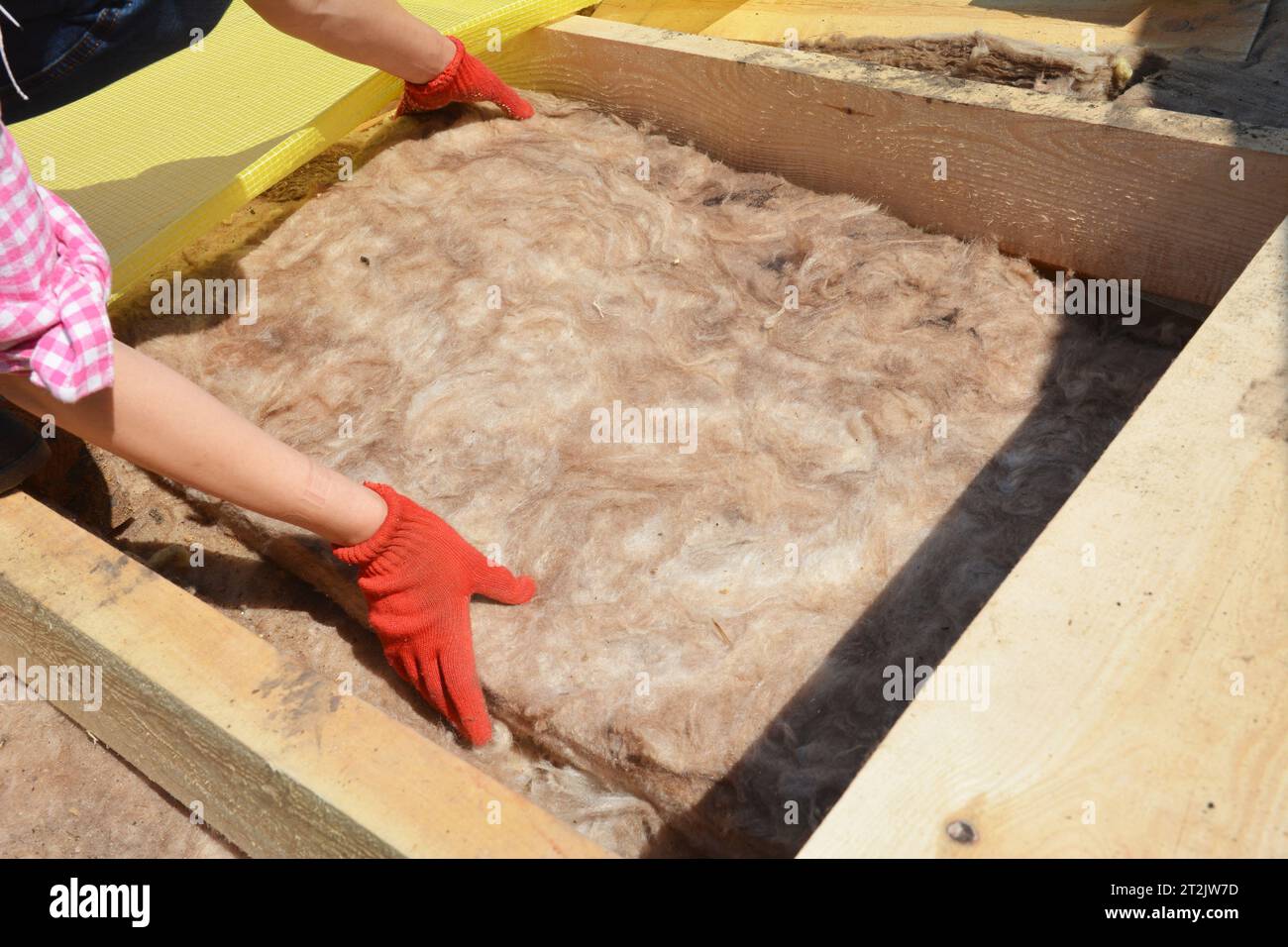 Roofing contractor laying mineral wool insulation during house attic ...
