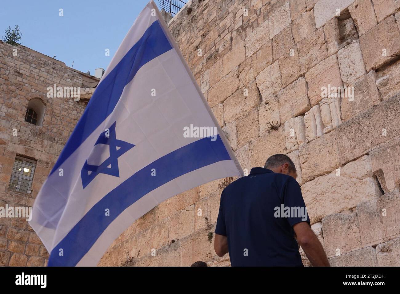 A religious Jew holds the Israeli flag as he takes part in a special prayer for the safe return ...