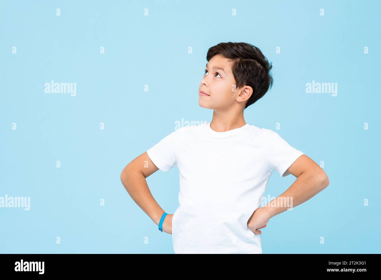 Handsome mixed race boy thinking and looking up with arms akimbo in ...