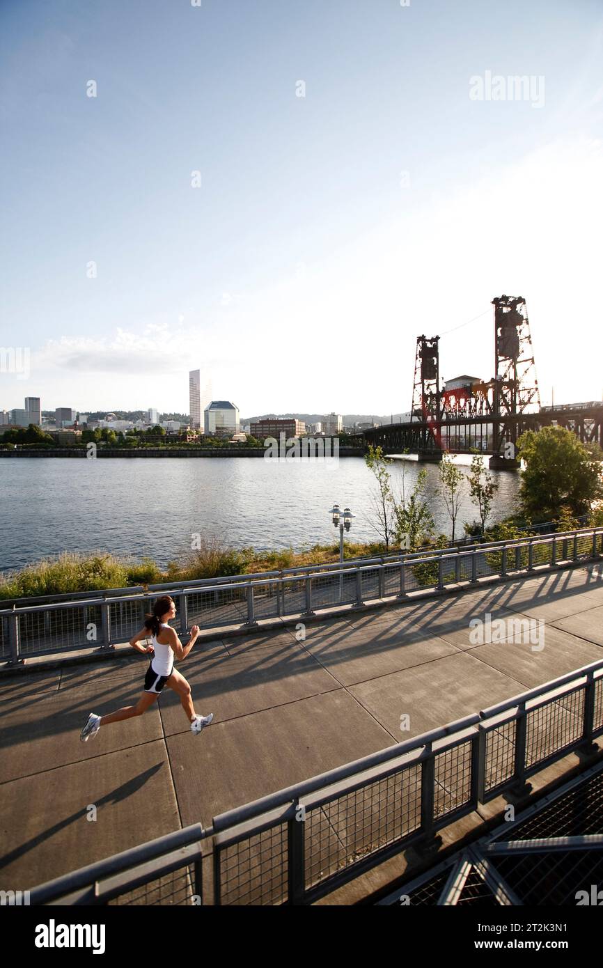 A woman running along a path near the water with the city in the ...