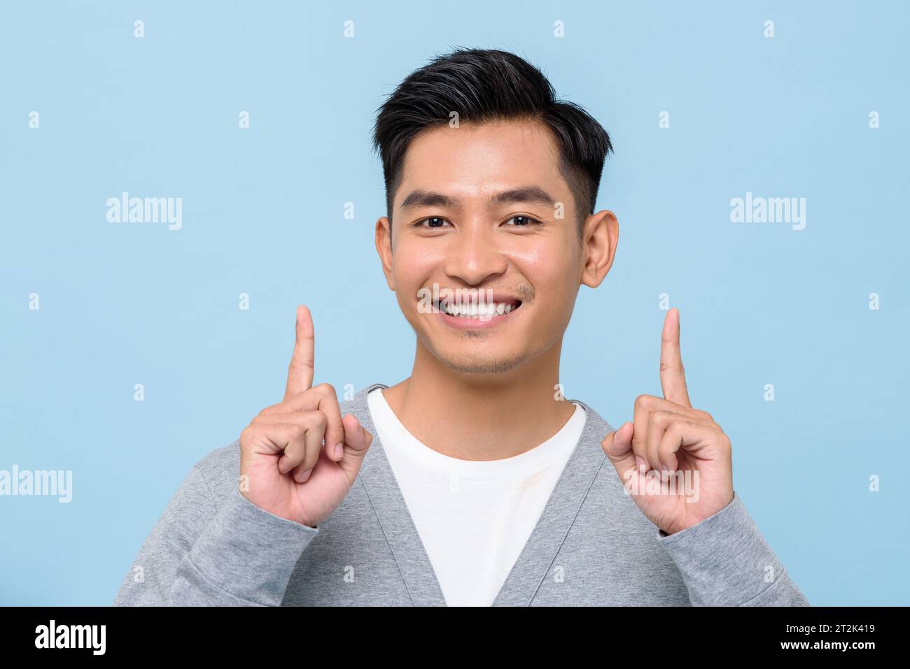 Handsome southeast Asian man smiling and pointing hands up in isolated ...