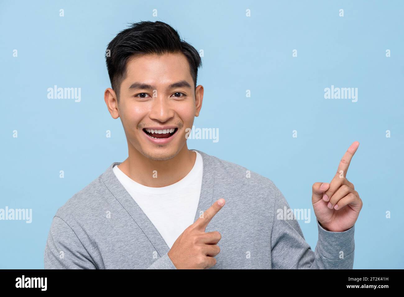 Handsome southeast Asian man smiling and pointing hands up in isolated ...
