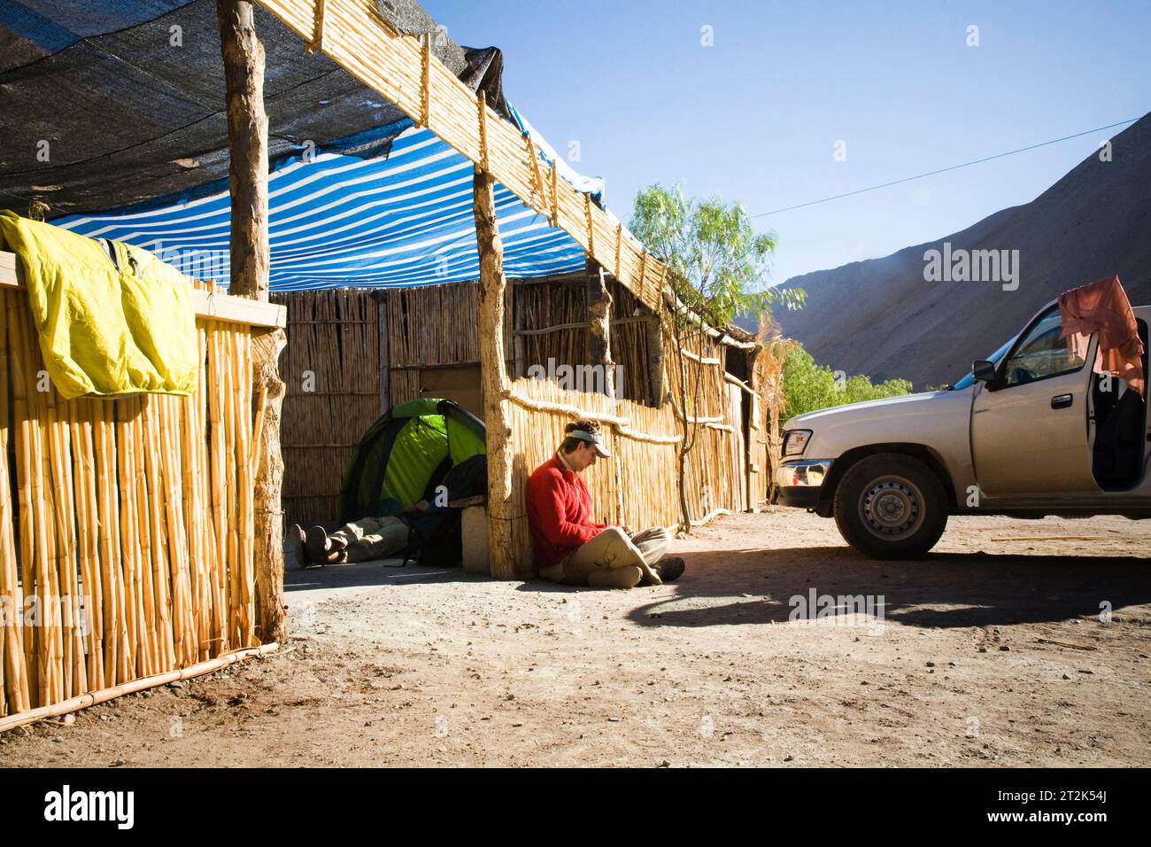Two young men rest alongside an open air shack, which doubles as a ...