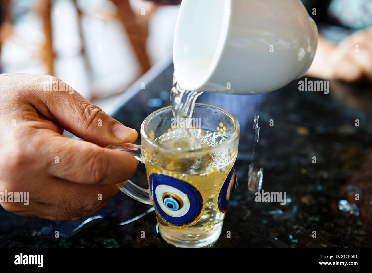 Close-up of hand pouring tea into glass cup Stock Photo - Alamy