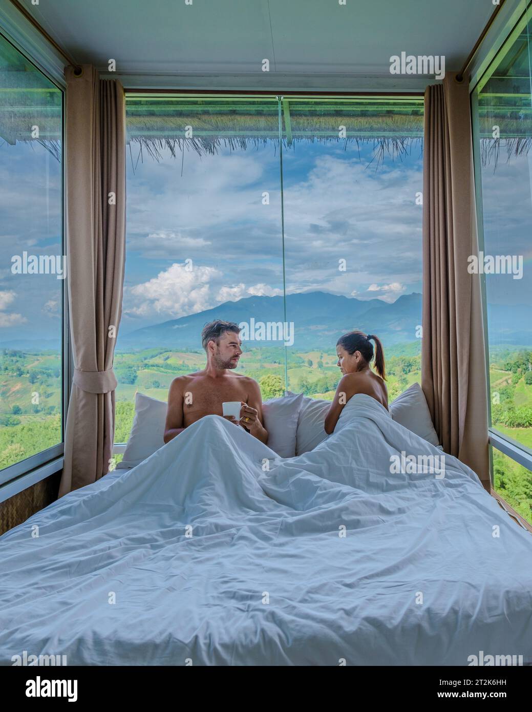 a couple of men and women laying in bed with open widows looking out ...