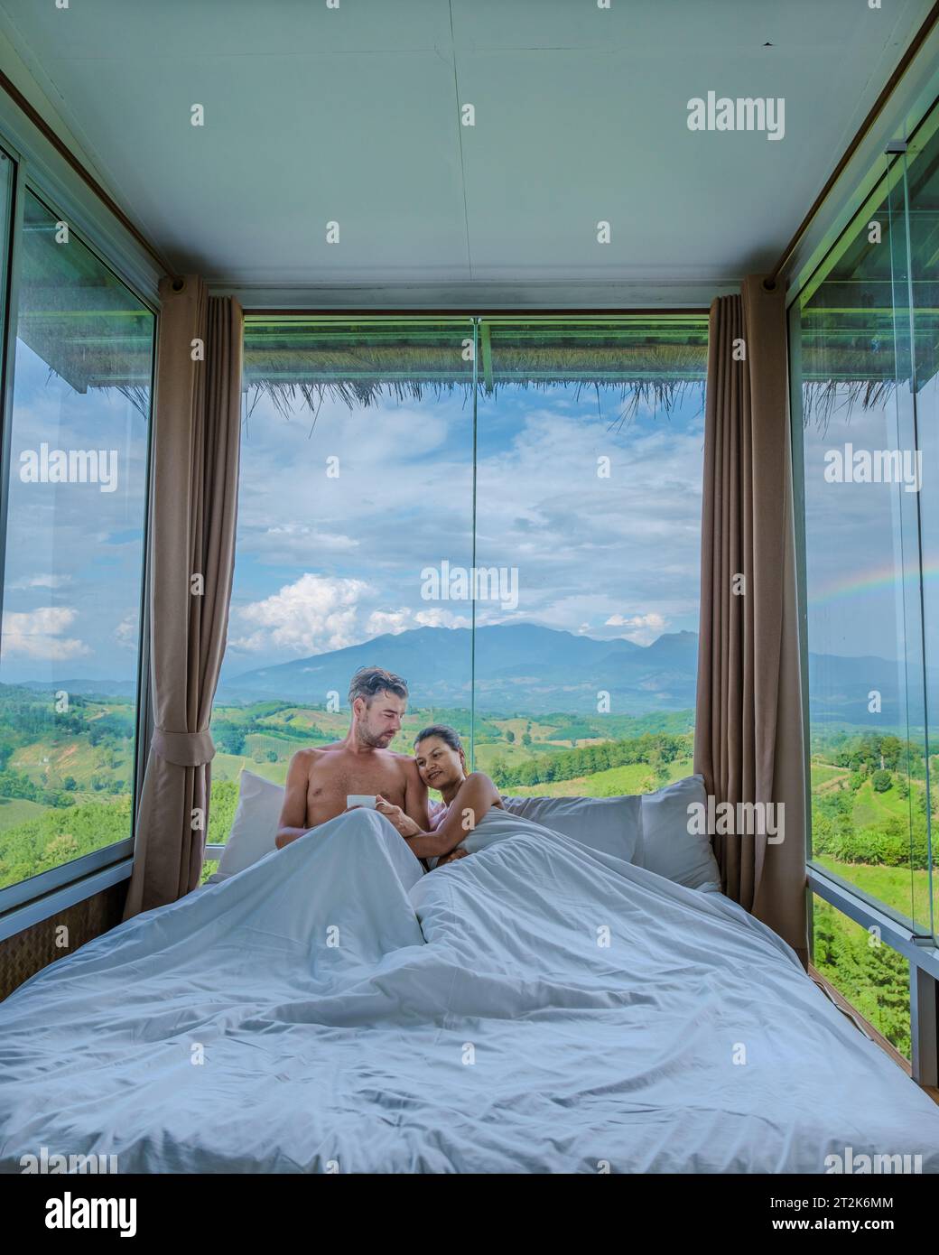 a couple of men and women laying in bed with open widows looking out ...