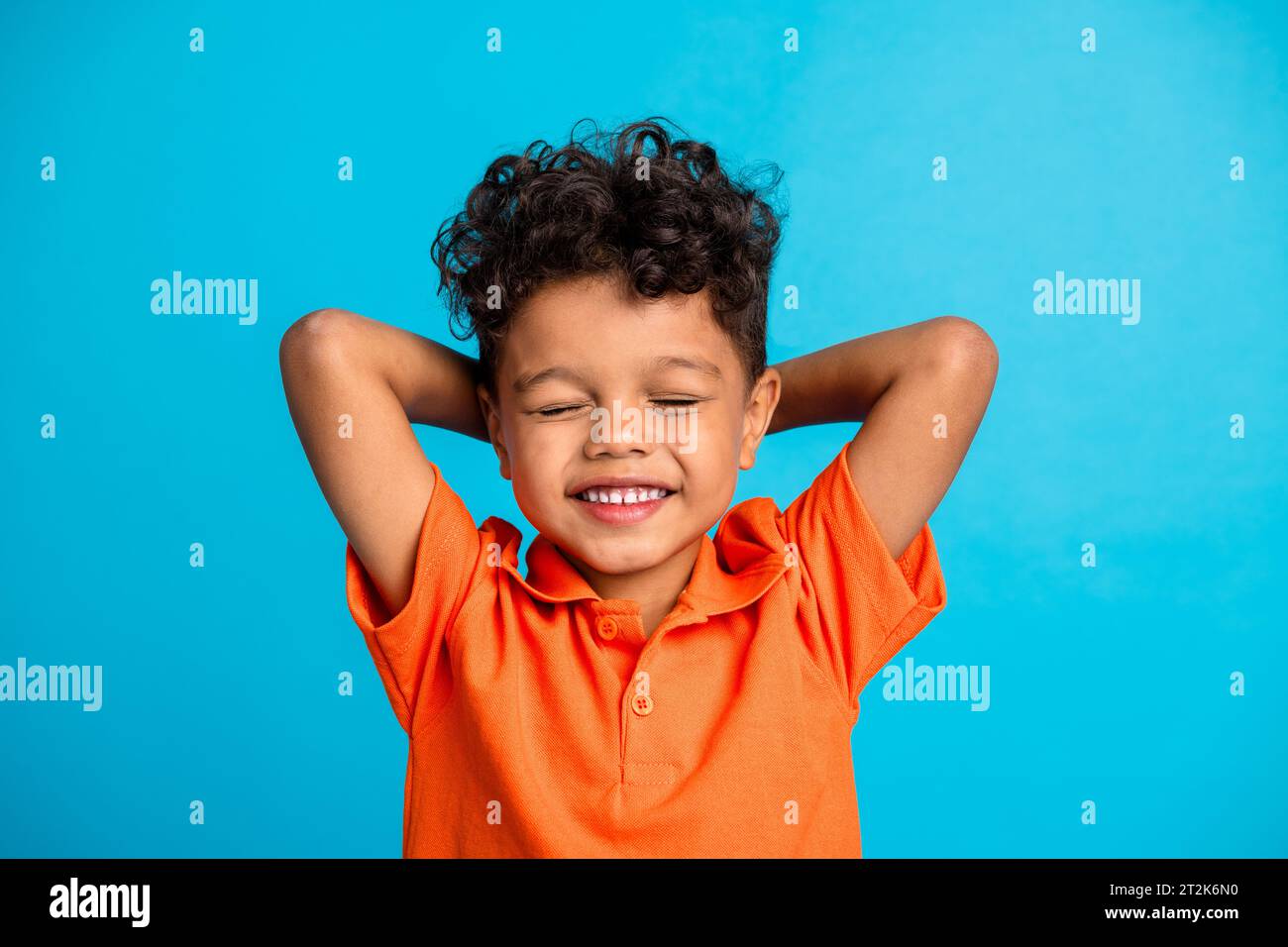 Photo of calm child boy sleeping relax hands over head isolated on blue ...
