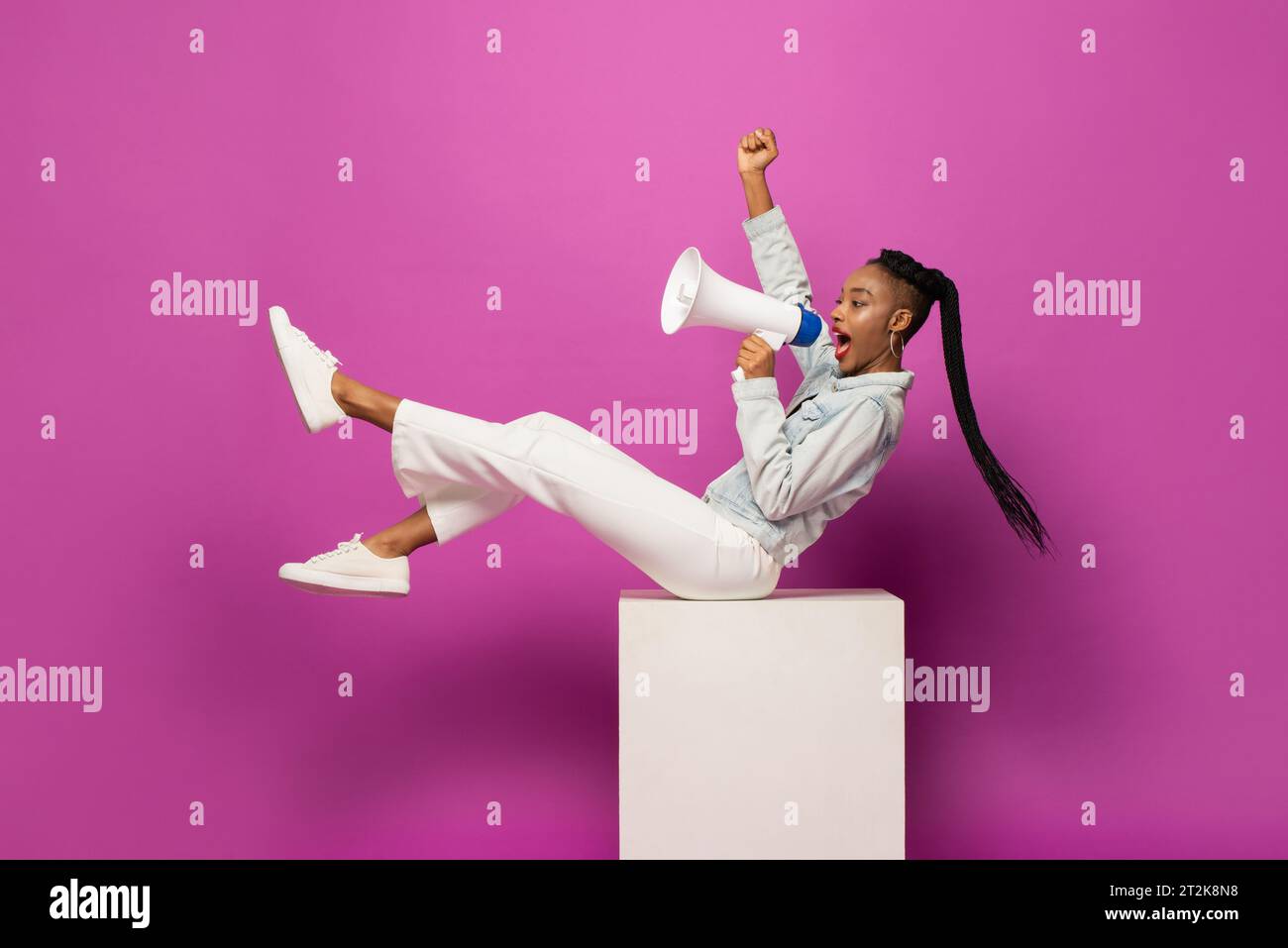 Young African American woman shouting on megaphone and raising fist in ...