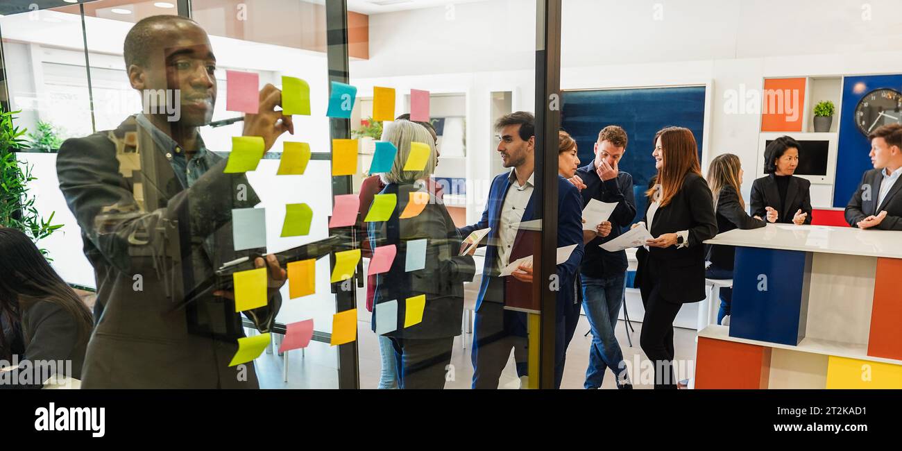 Multiracial colleagues working inside business office with glass walls ...