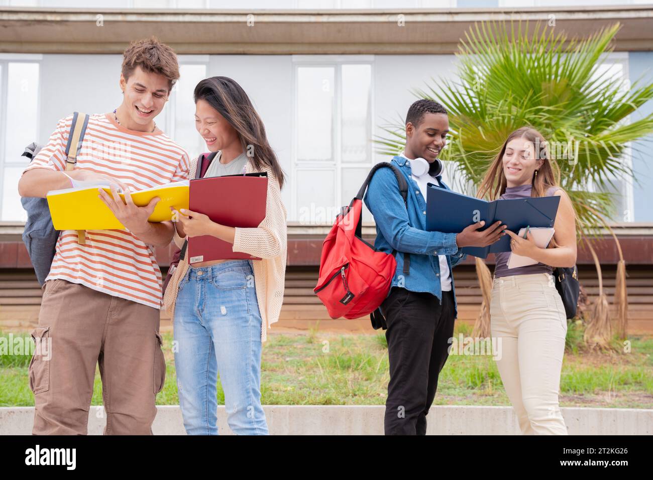 Multiracial group of four happy teenage students talking with college ...