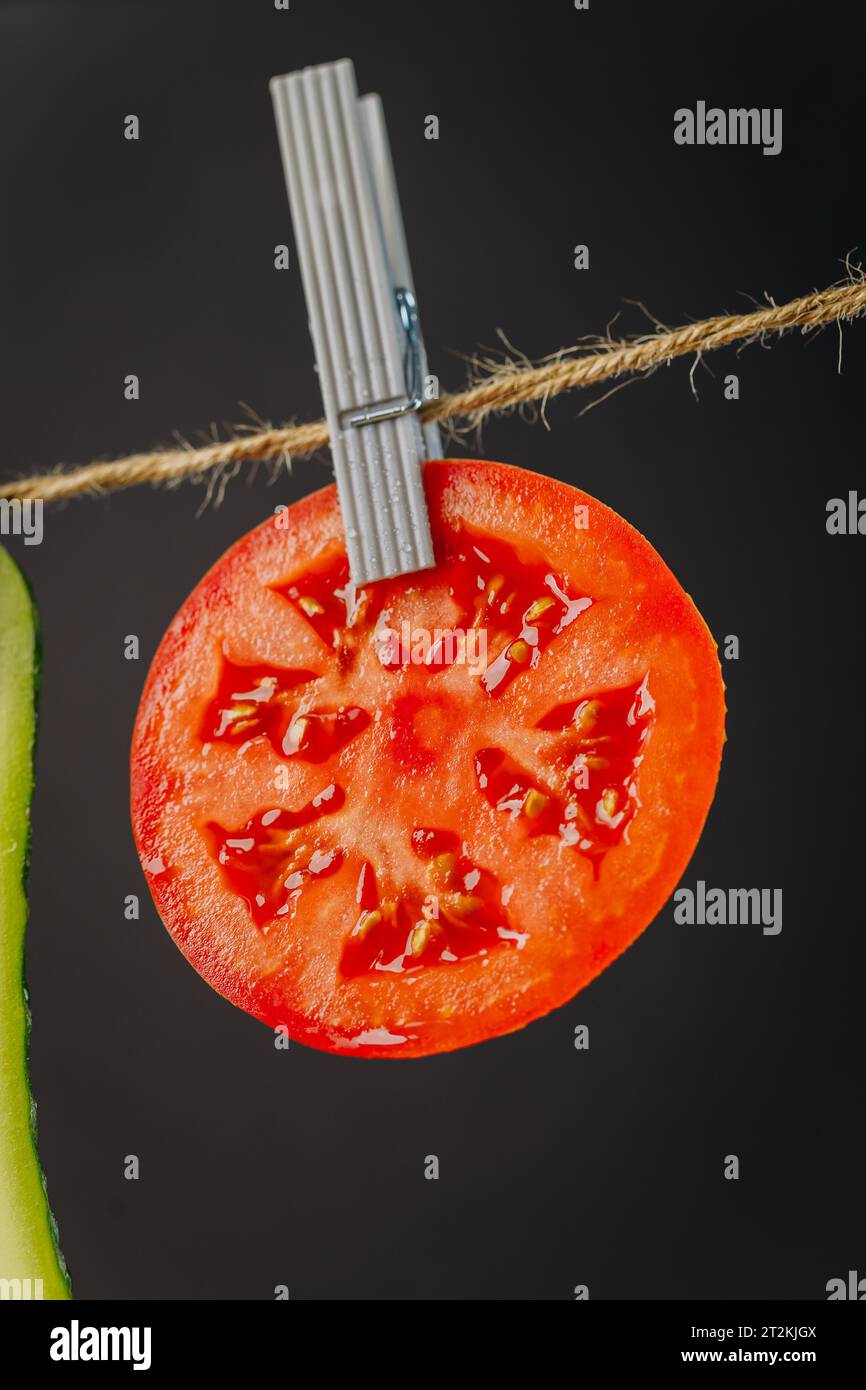 Sliced tomato is hanging by a thread on yellow background Stock Photo ...
