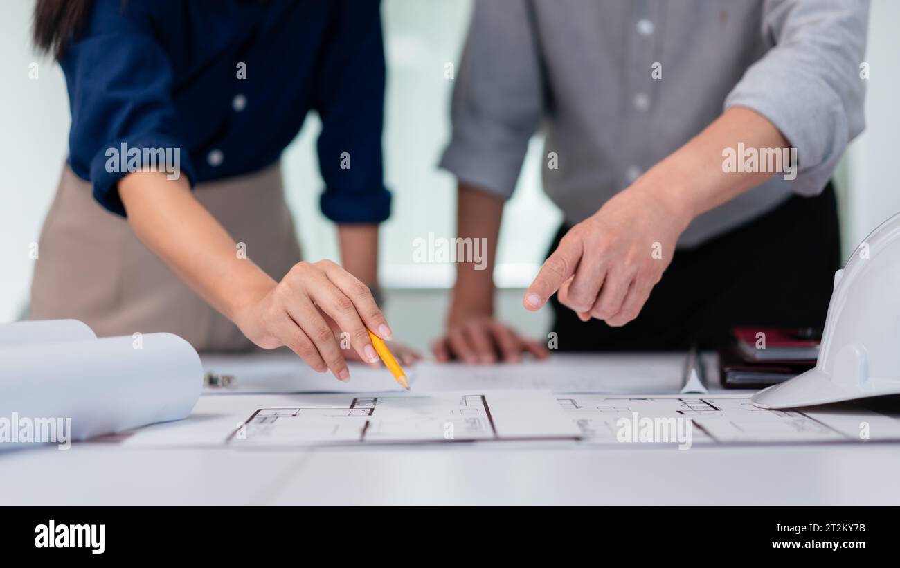 Two Architects Pointing On Blueprint To Discuss And Planning About Construction Building Project